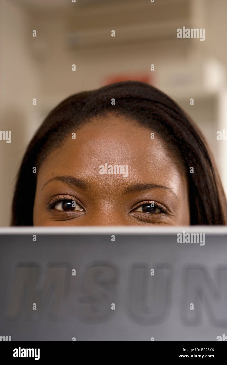 Woman peering over laptop hi-res stock photography and images - Alamy