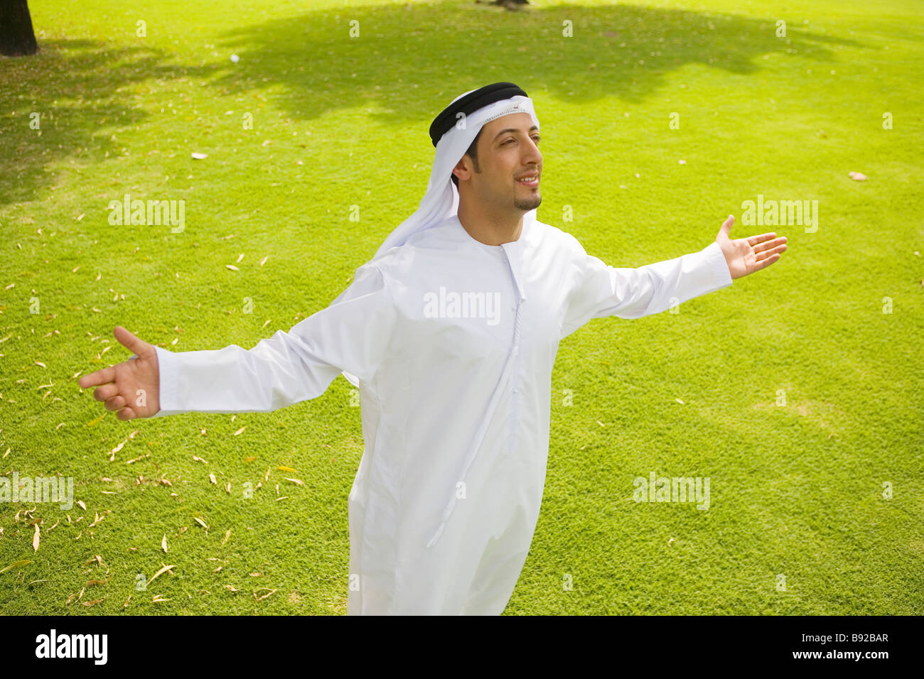 Arab man standing in a park arms outstretched Stock Photo - Alamy