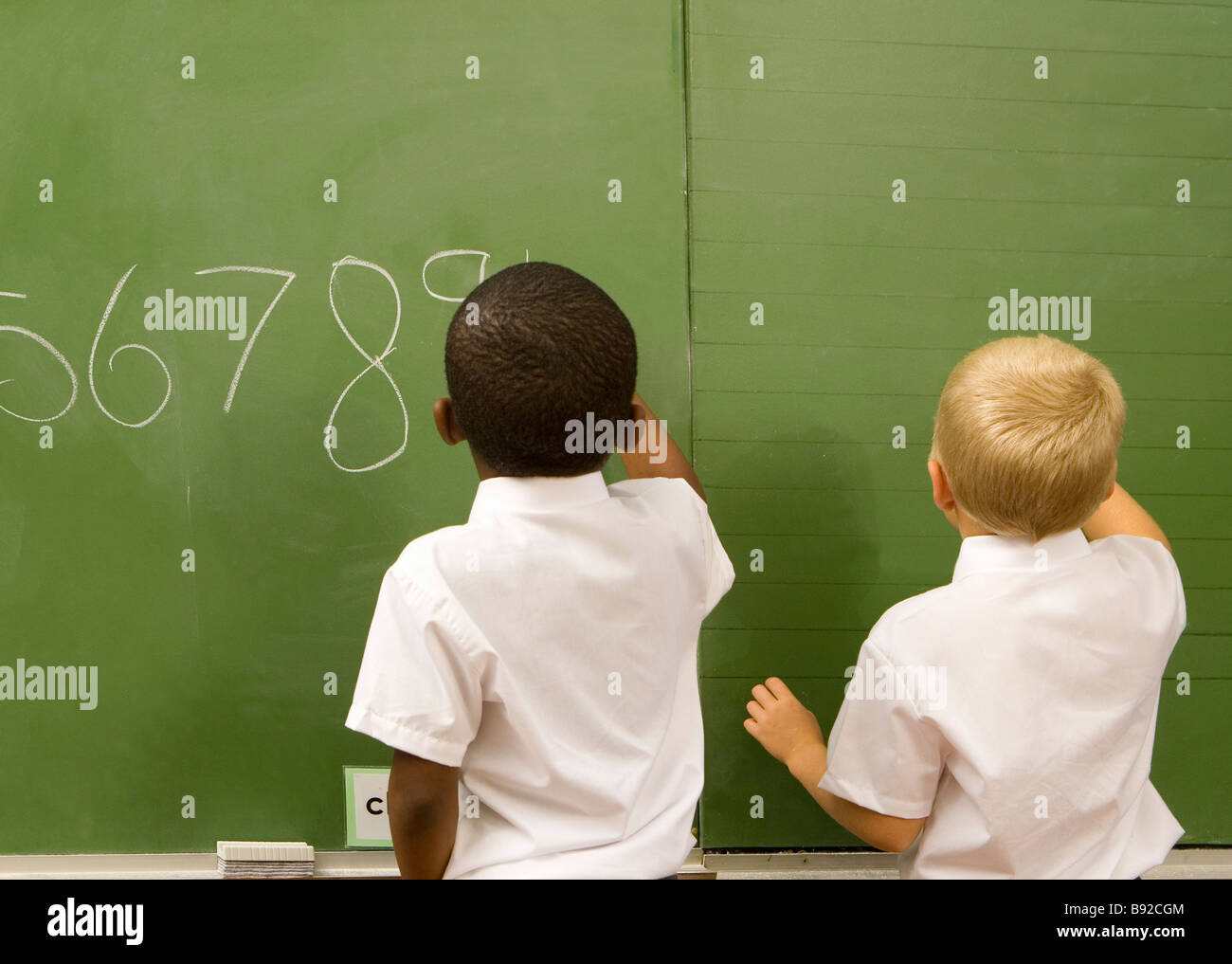 Young African and Caucasian Boys Writing on a Classroom Blackboard ...