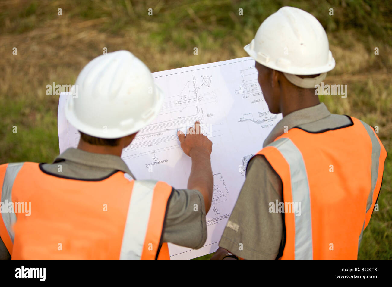 Rear view of two construction workers working at construction site hi ...