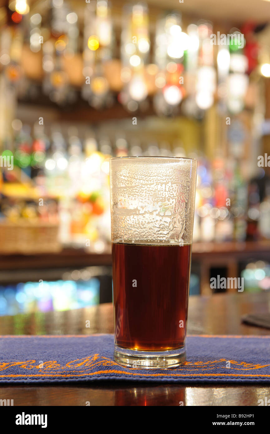 half empty pint glass of beer sitting on bar in a pub Stock Photo - Alamy
