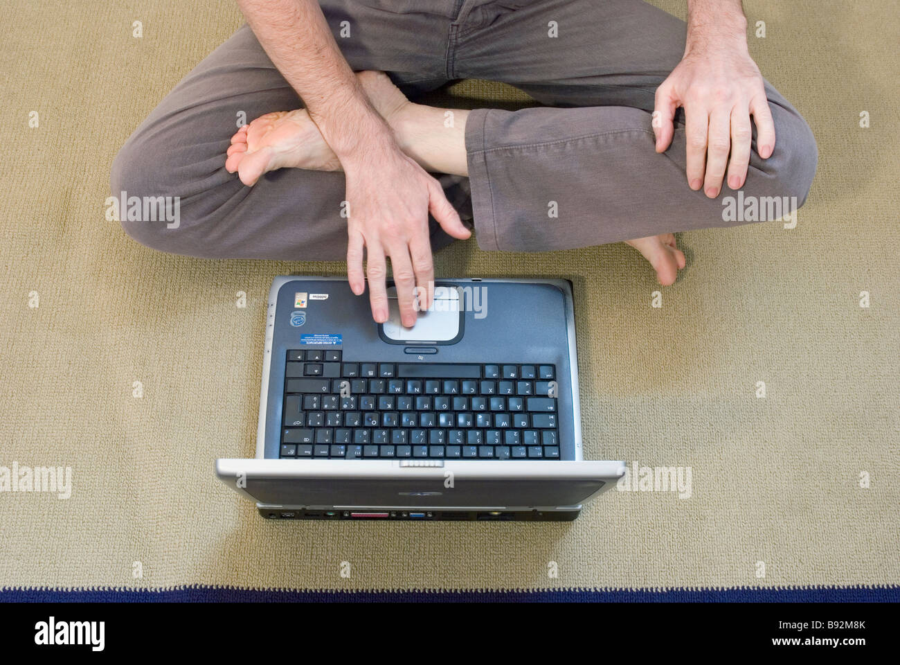 Man sitting cross legged on the floor using laptop Stock Photo - Alamy