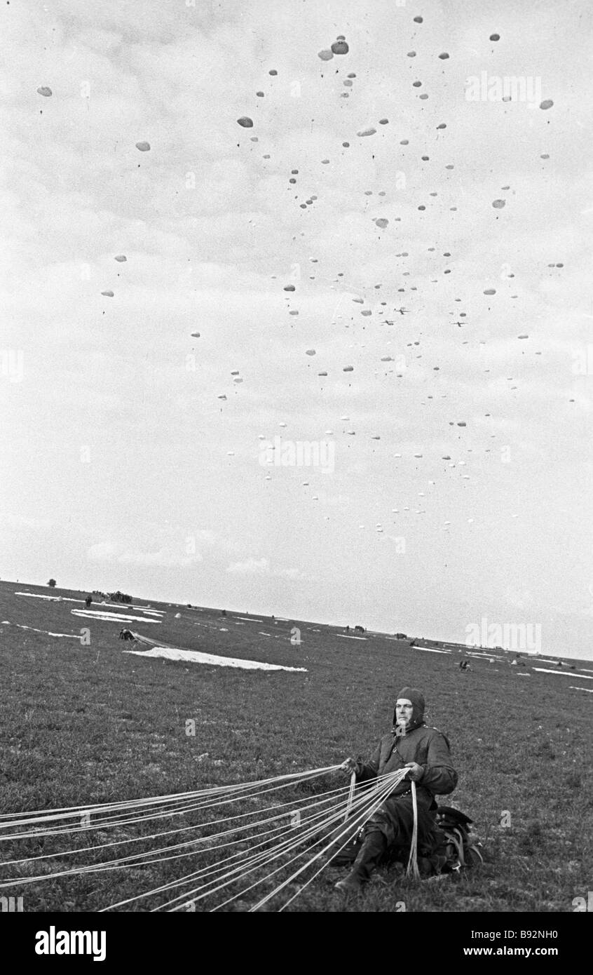 Paratrooper pulls parachute lines on the ground after airborne landing ...