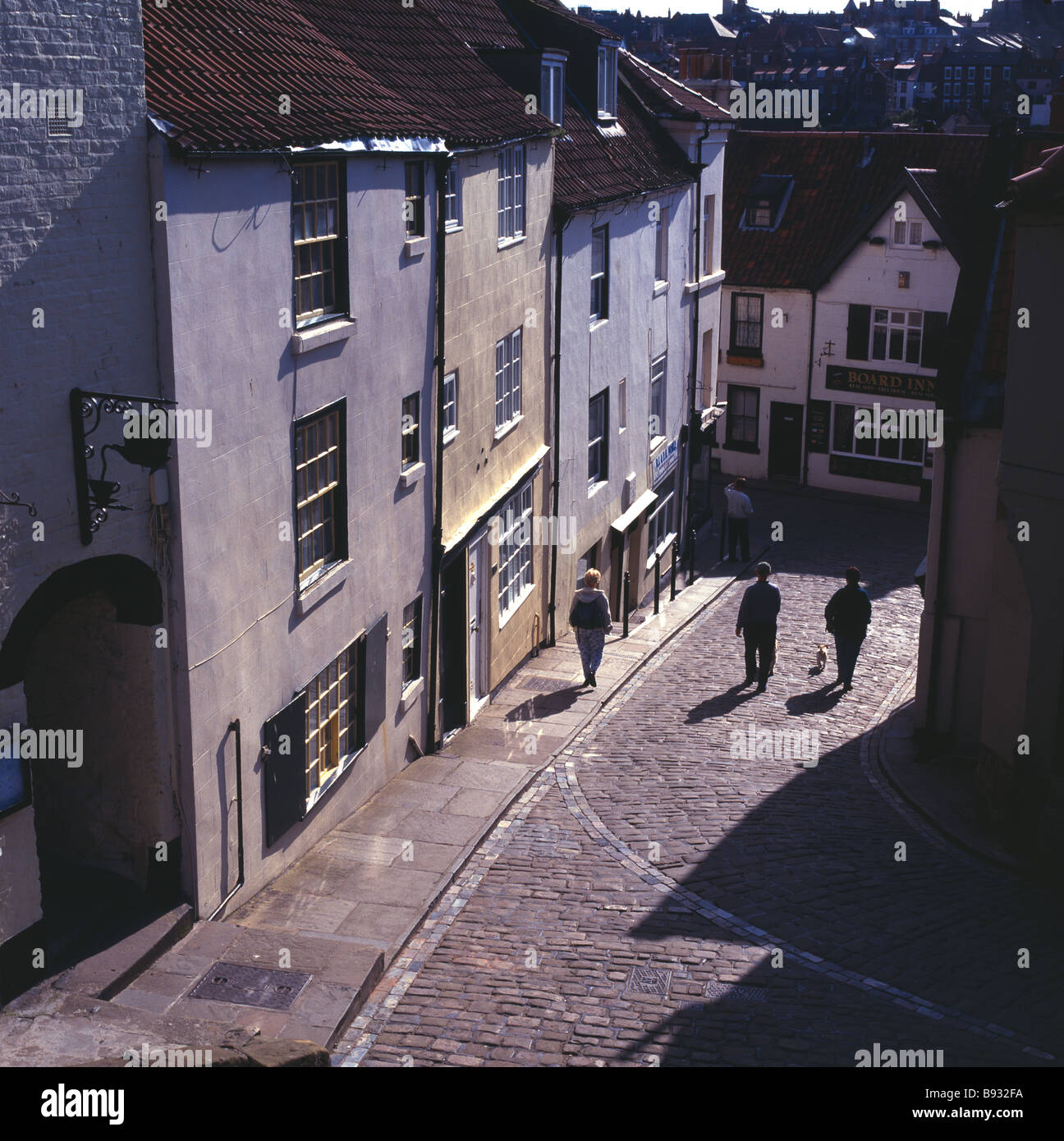 Three people and a dog silhouetted on Church Lane, Whitby, North ...