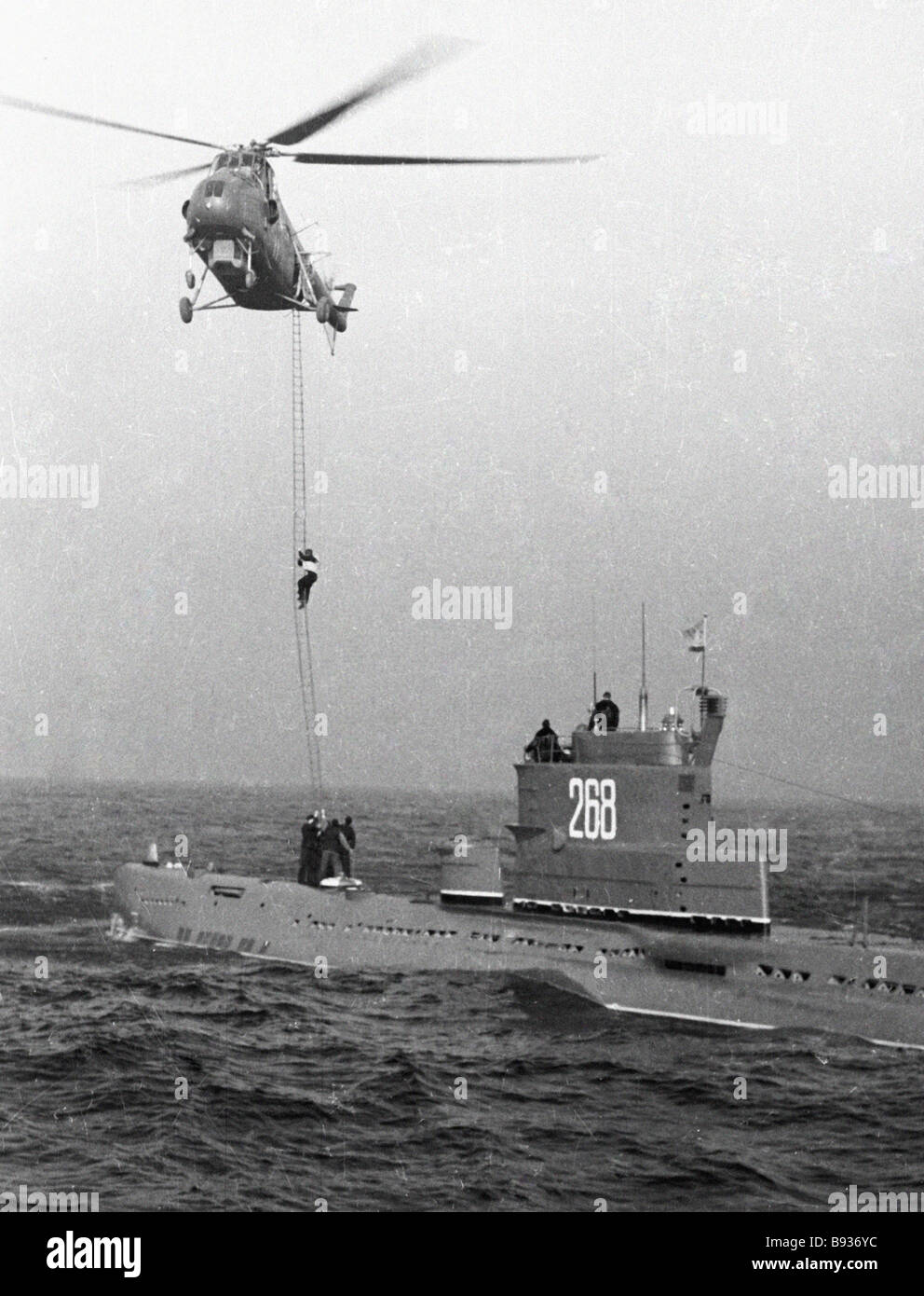A seaman gets down the rope ladder from a helicopter onto the submarine ...