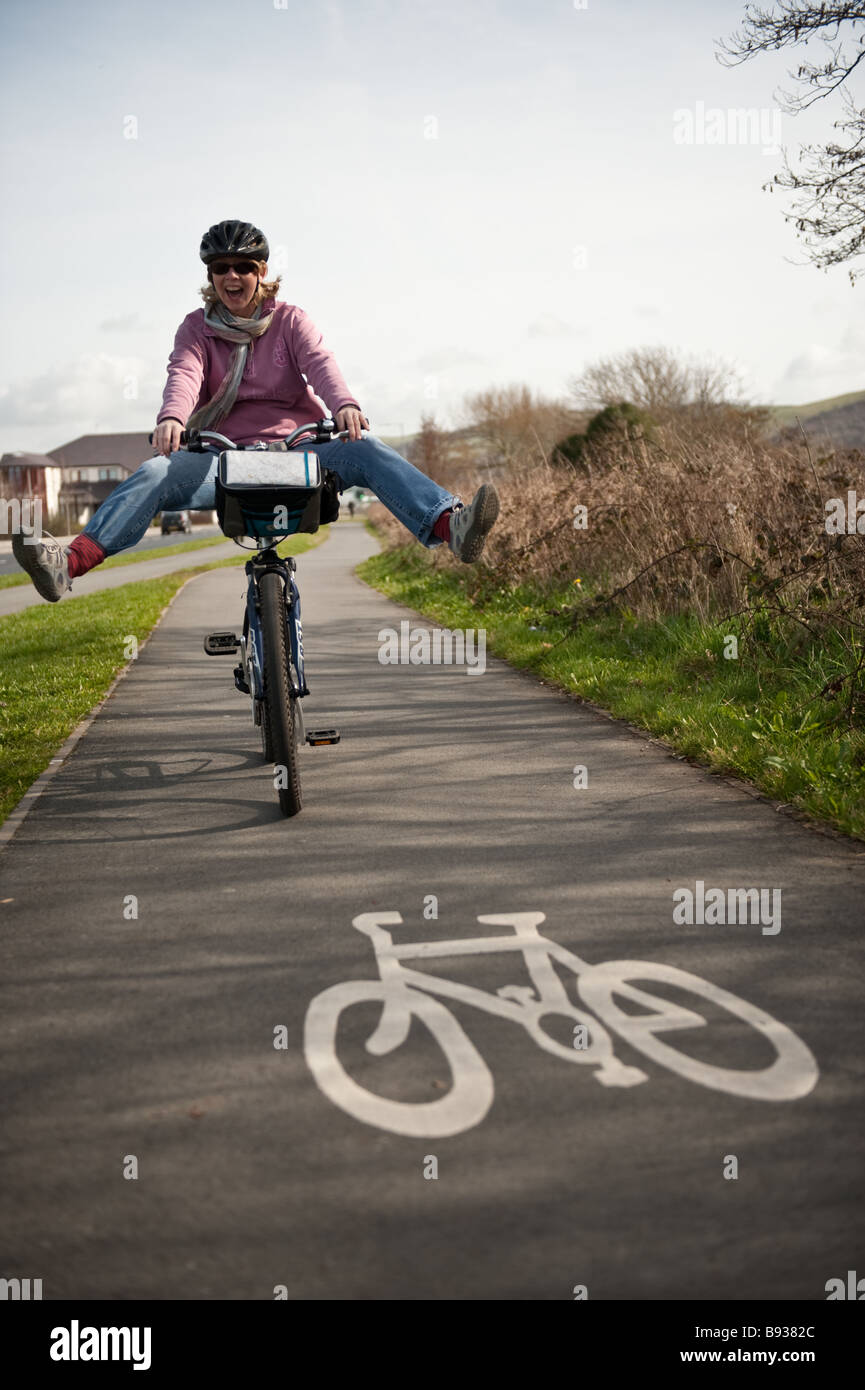 A happy woman cycling on the Rheidol Trail cycle path Aberystwyth Wales ...