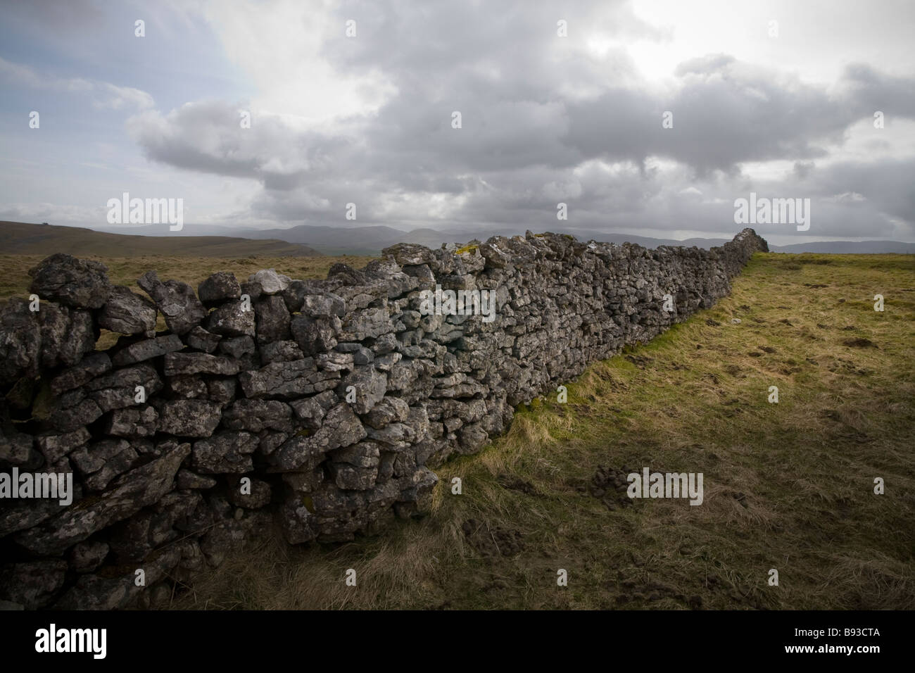 Dry stone wall going off into the horizon over rough fell grass ...