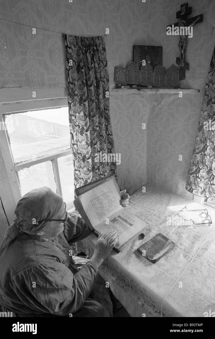 An old Northern woman reads an antique book kept in her house from ...
