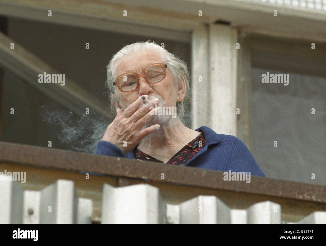 Elderly woman smoking on the balcony of veteran worker home No 31 Stock ...