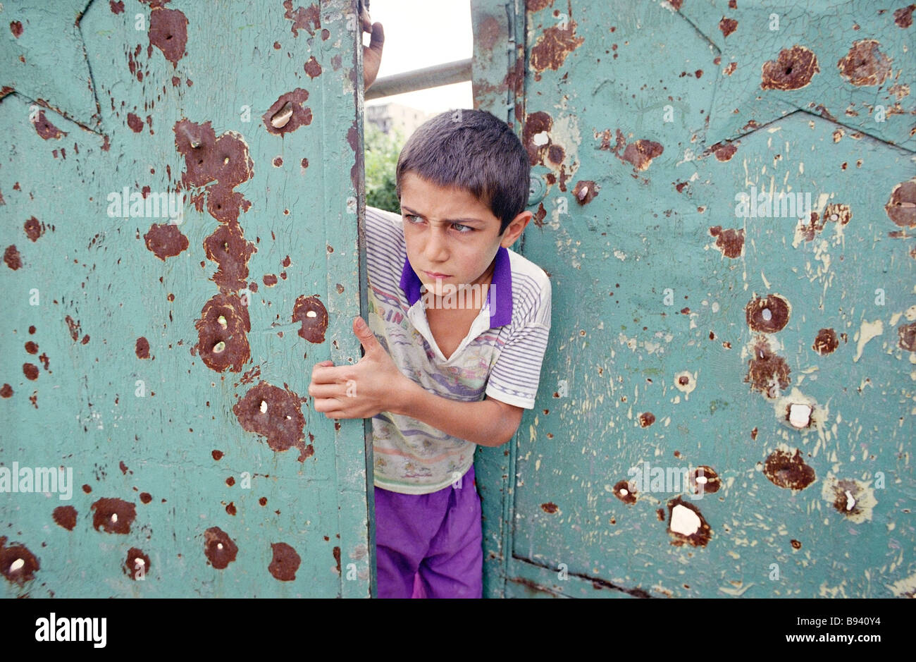 Child near the gate riddled with bullet holes Grozny city Stock Photo ...