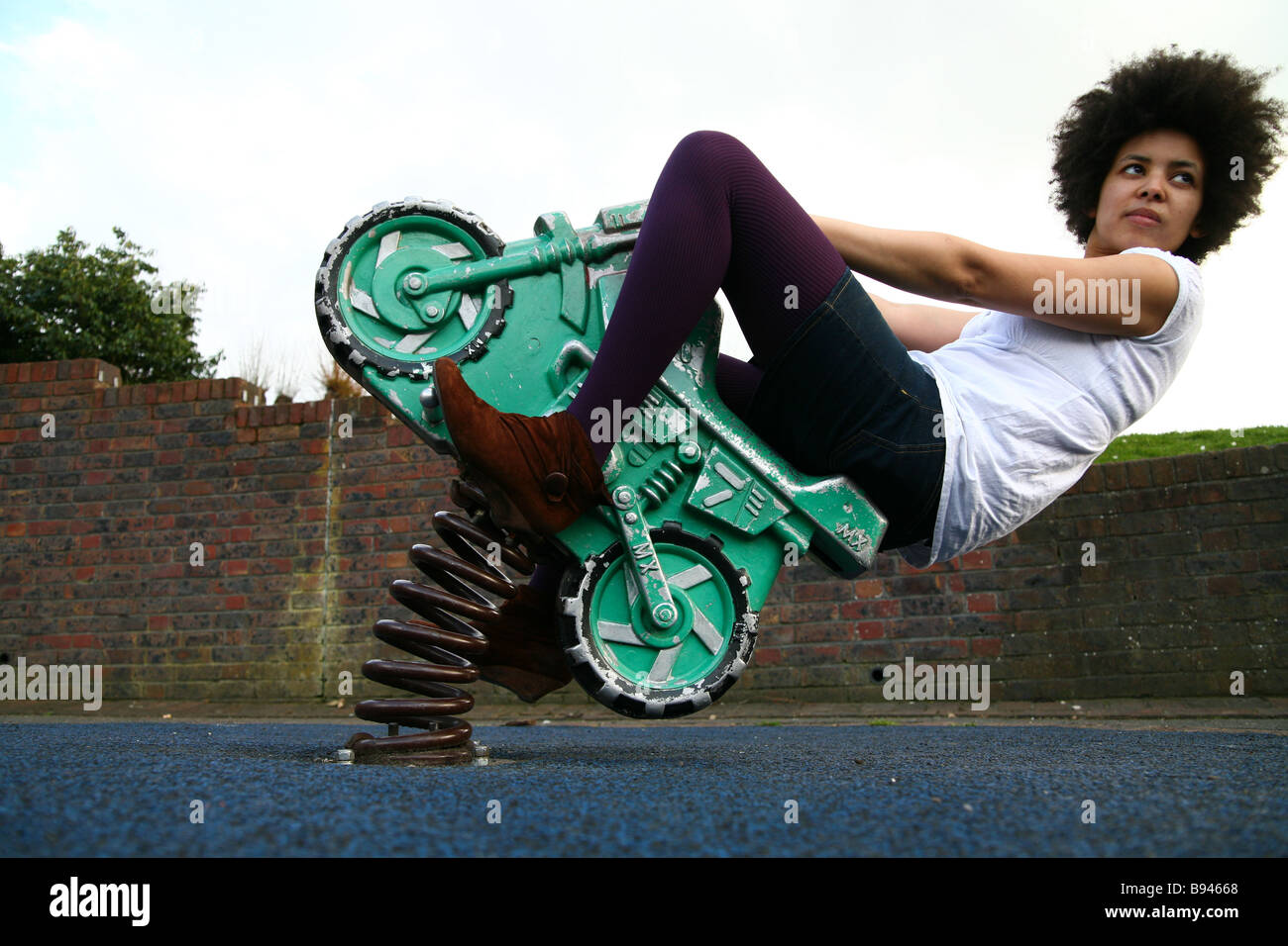 Black girl leaning back on playground motorcycle Stock Photo - Alamy