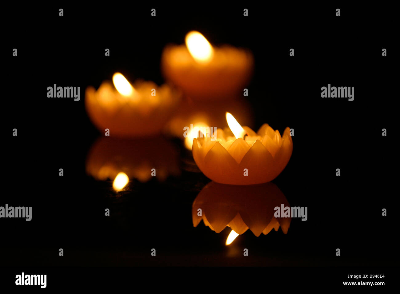 Three attractive candles on a black reflective surface Stock Photo - Alamy