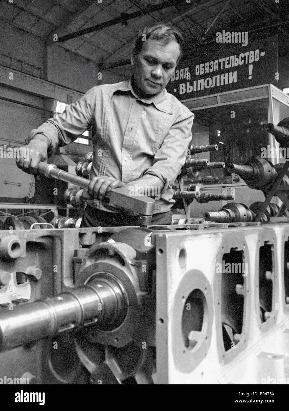 Assembly man placing crankshafts on the assembly line of diesel engines ...