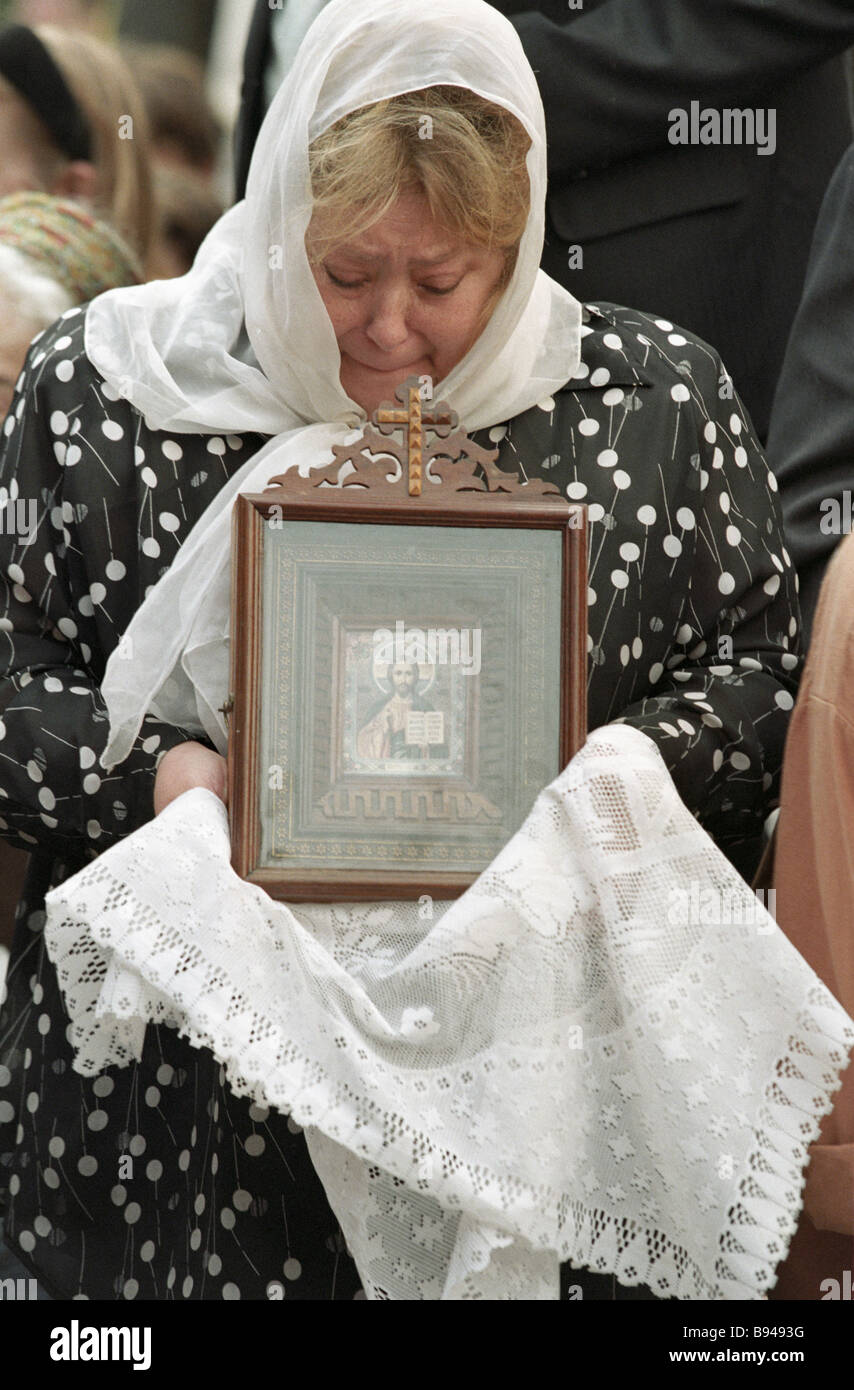Woman with icon in the funeral procession during the burial of remains ...