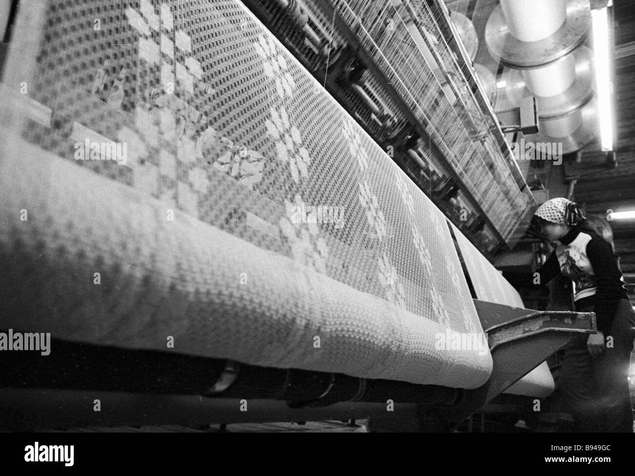 A worker at the loom with ready veil curtain and veil factory room ...