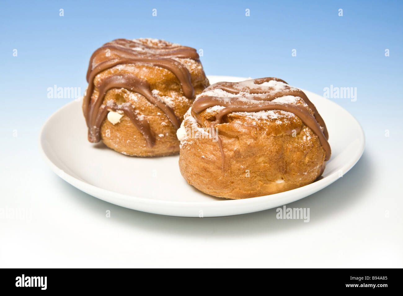 Cream buns on a blue studio background Stock Photo - Alamy