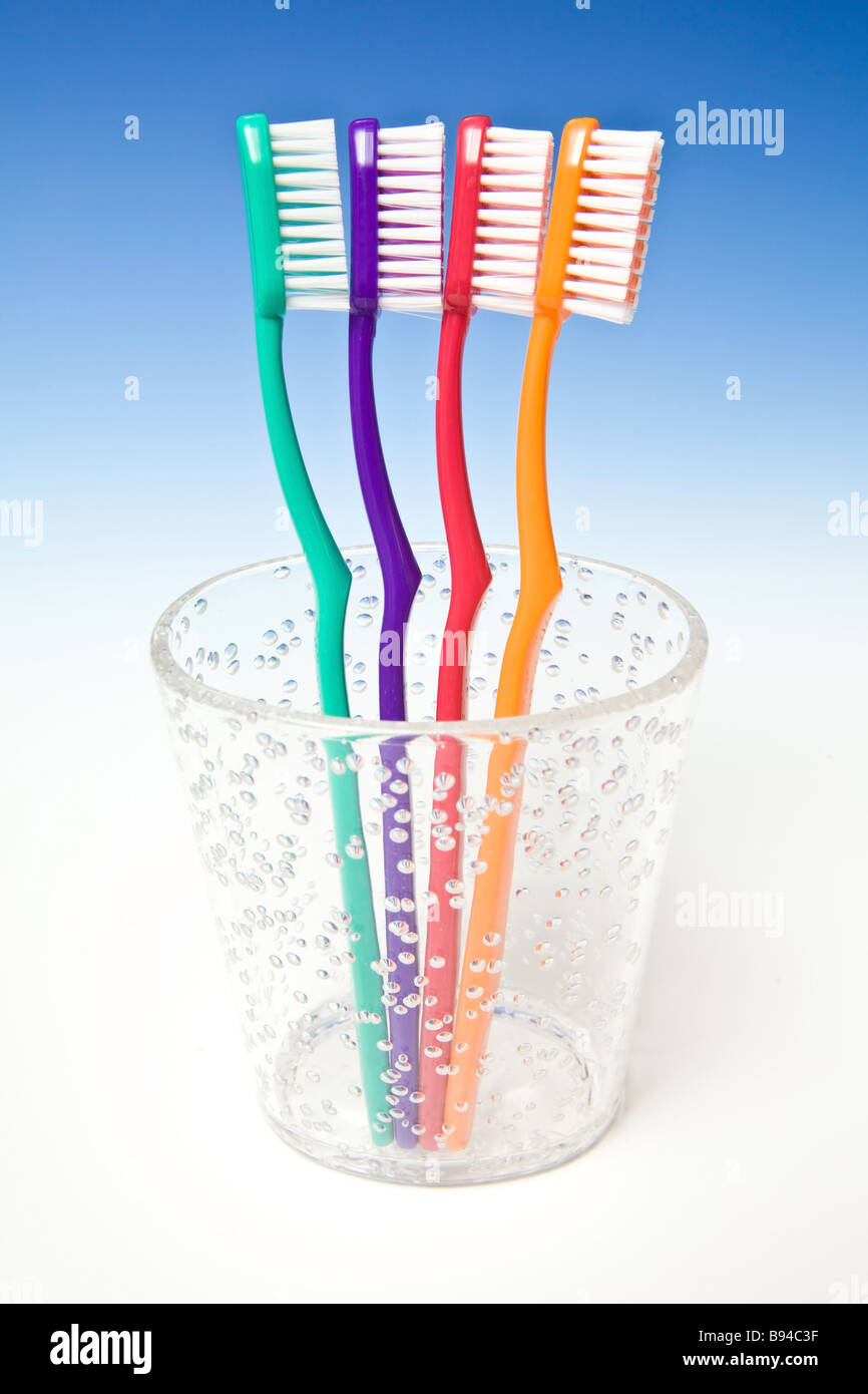 Colored tooth brushes in a cup on a blue studio background Stock Photo ...