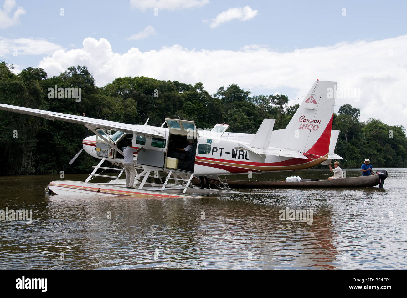 A Caravan float plane unloads gear and passengers into a Wai-Wai Indian ...