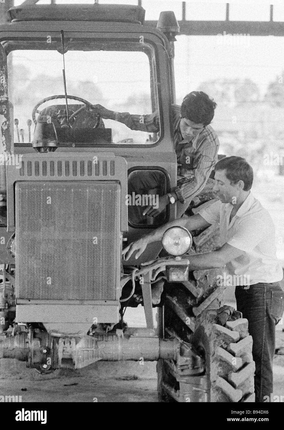 A Soviet specialist explaining to a Cambodian tractor driver how the ...