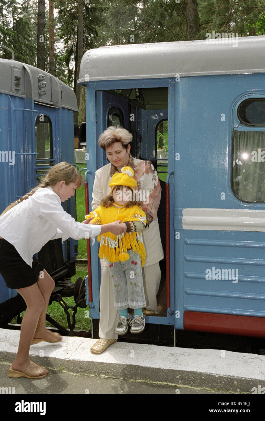 Little conductor helps a passenger with a child get out of the carriage ...