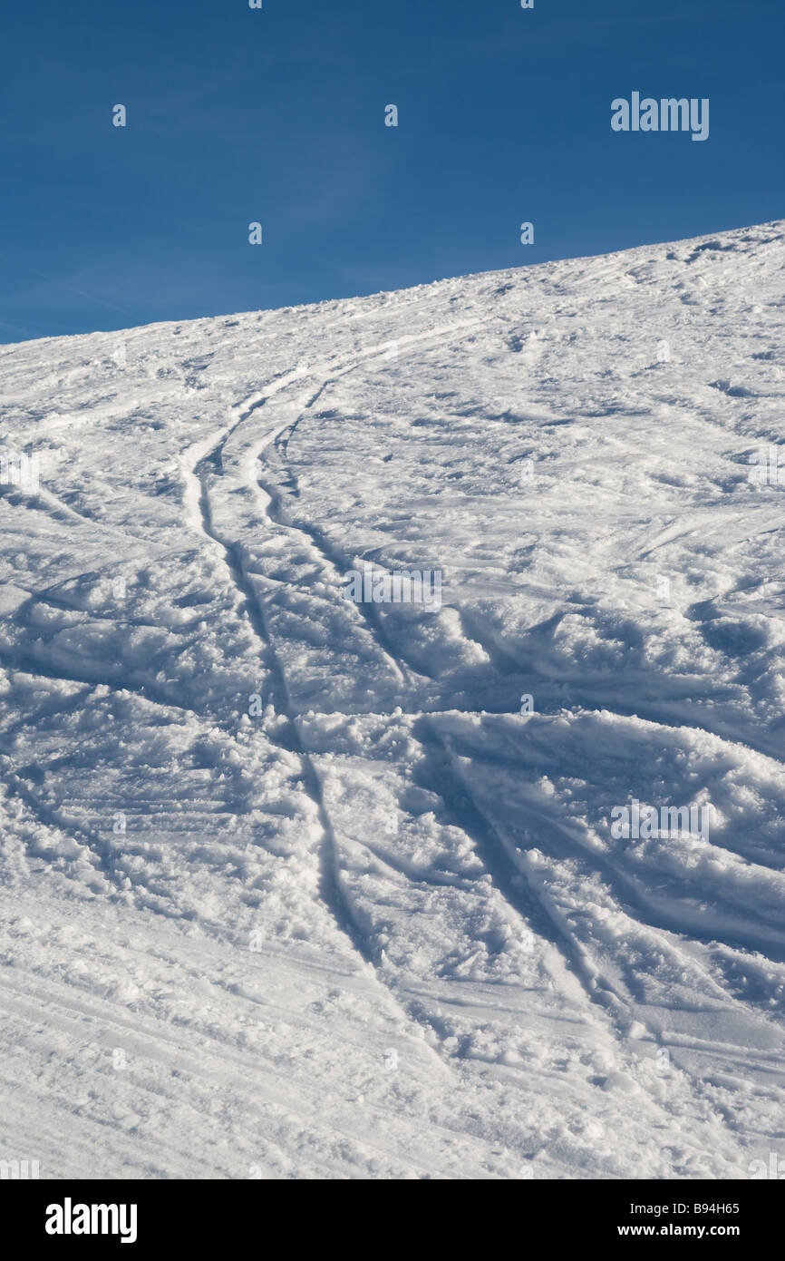 A snowy slope with many ski tracks criss crossing the scene in every ...