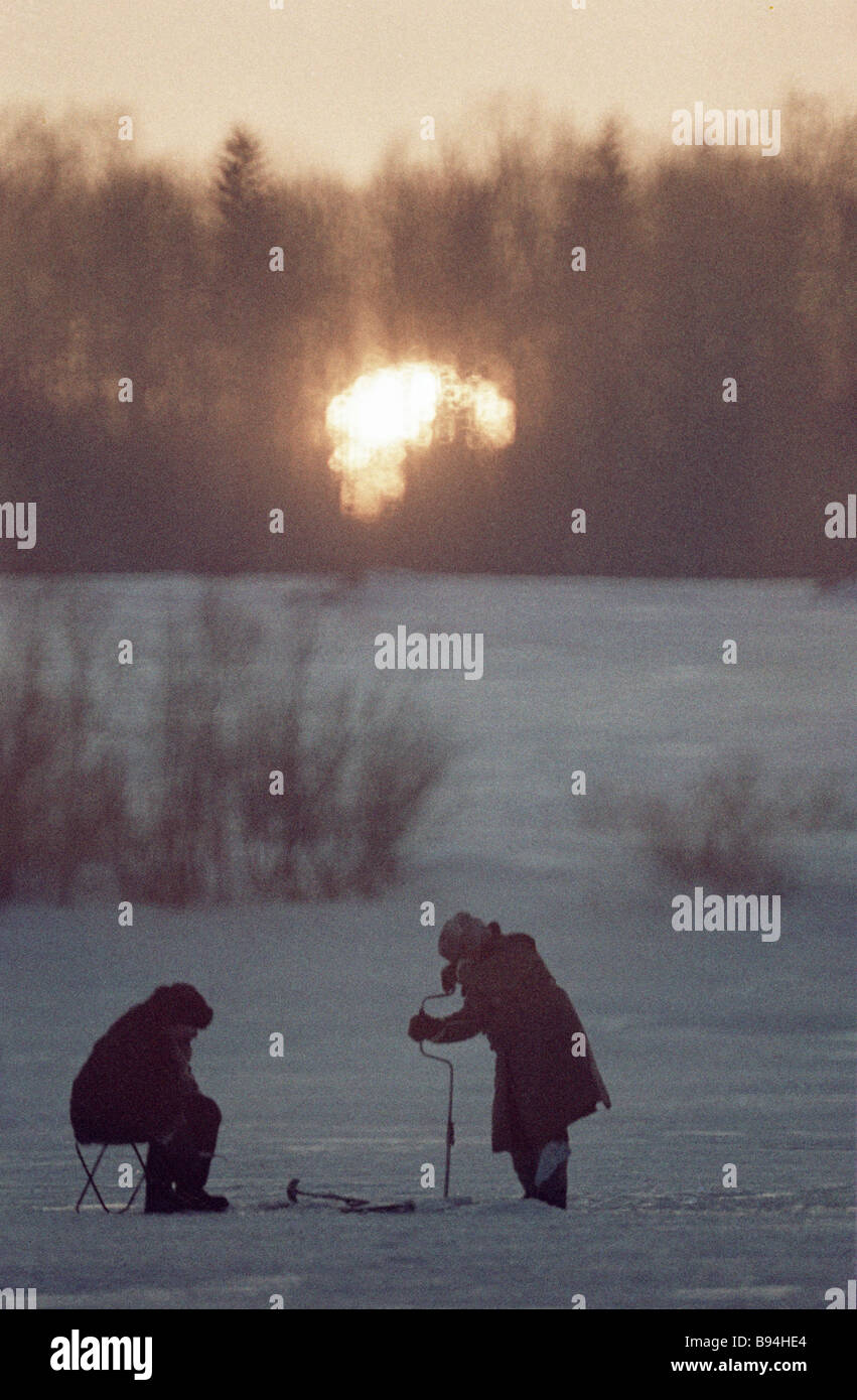 Fishermen breaking an ice hole at dawn Stock Photo - Alamy