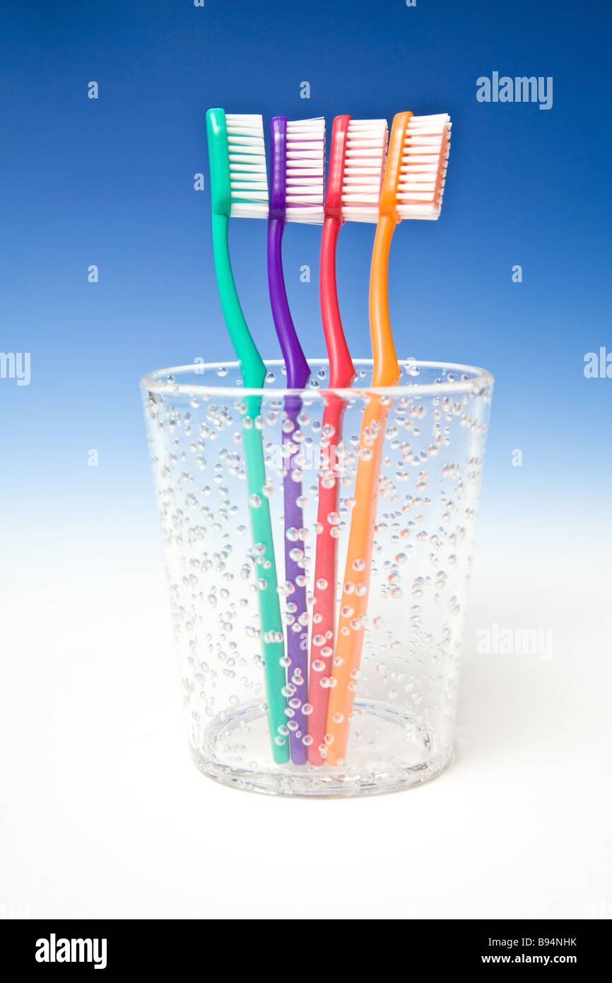 Toothbrushes in a cup on a blue studio background Stock Photo - Alamy