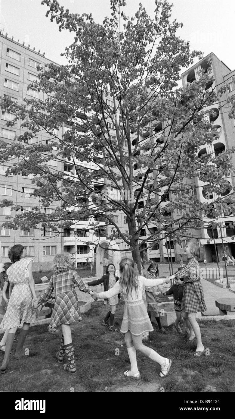 Children in merry go round around a trees in the year of a new housing ...