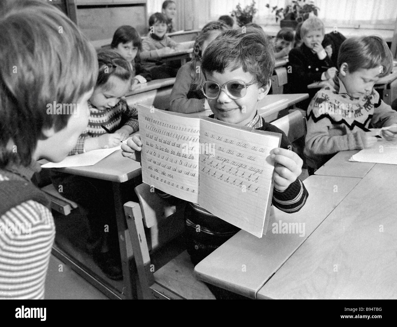 A zero grade pupil showing his notebook to a classmate at secondary ...