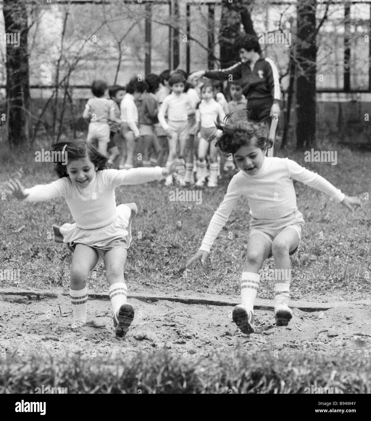 Children do long jumps at a physical training class in primary school ...