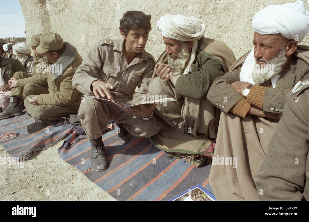 Soldiers of a military unit speaking to elders in an Afghan village ...
