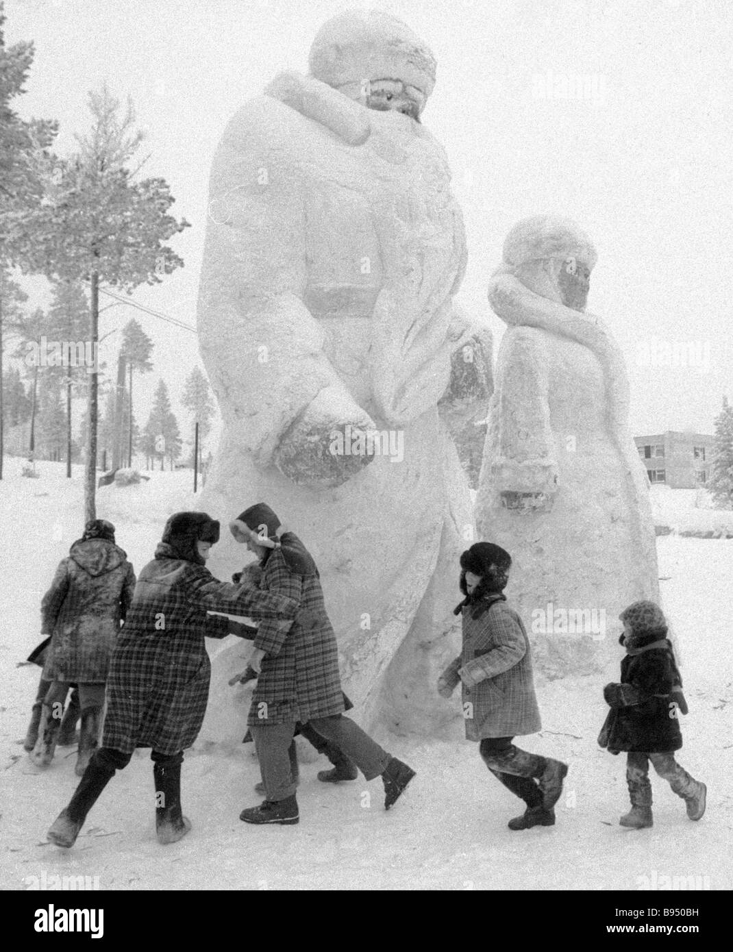 Children playing in a park round Father Frost and Snow Maiden statues ...