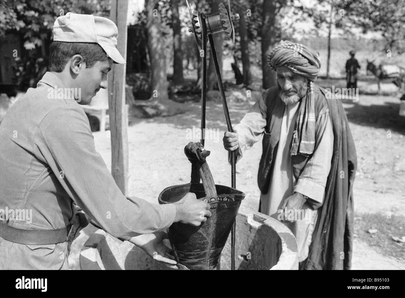Soviet soldier helps an Afghan get water from a well Stock Photo - Alamy