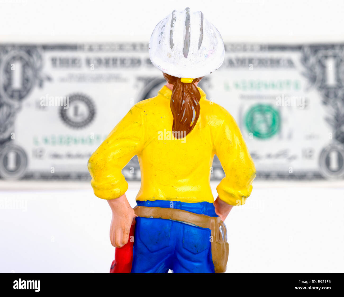 A working woman figurine and a US dollar bill Stock Photo - Alamy