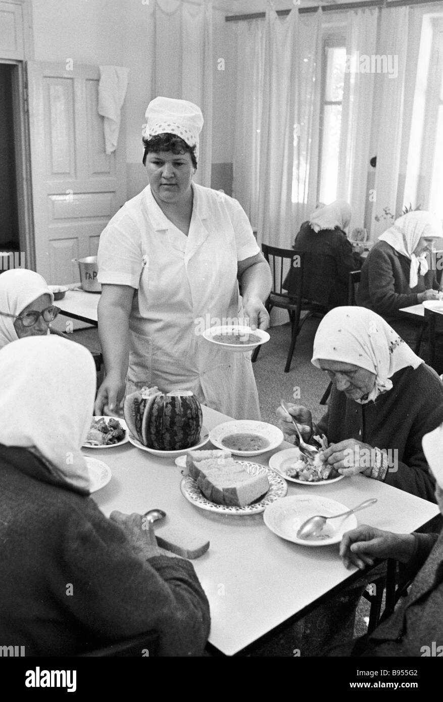 A waitress bringing a plateful of soup to elderly women sitting at a ...