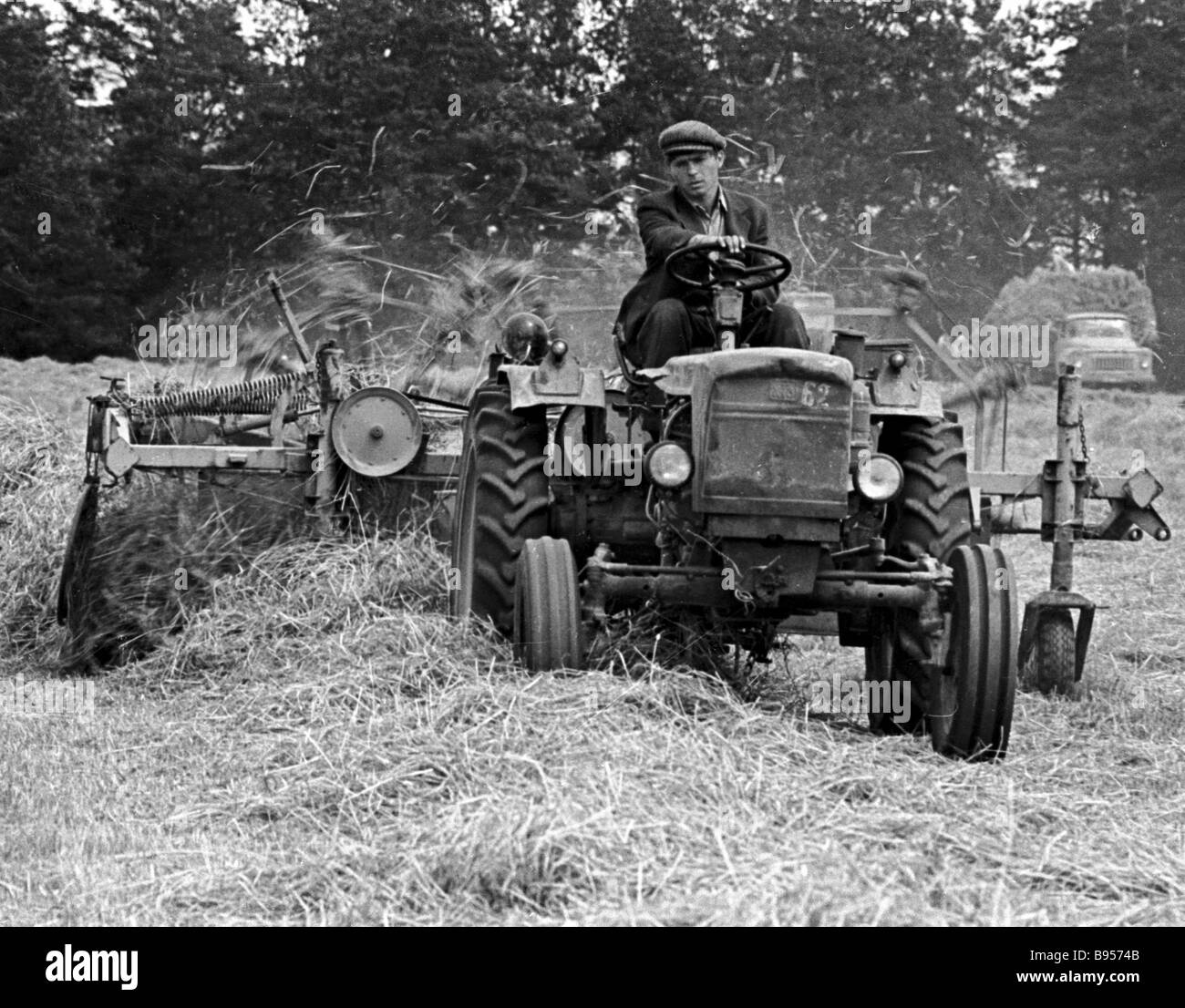An operator of a tractor with a trailer collecting cut grass in the ...