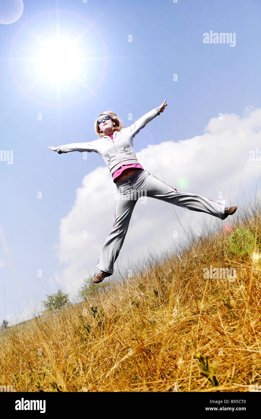 Happy woman jumping against blue sky Stock Photo - Alamy