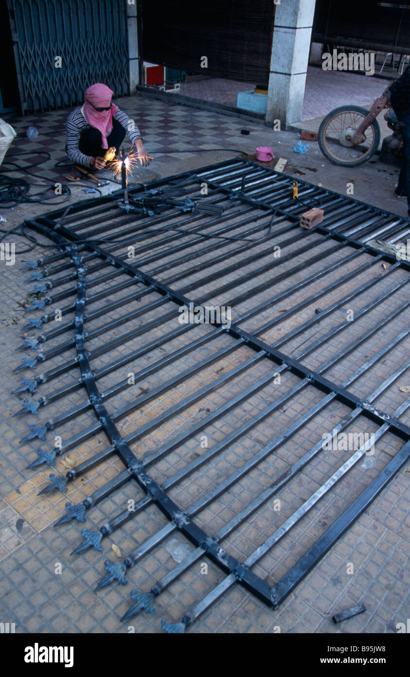 CAMBODIA Siem Reap Man welding a metal gate which is lying on the ...