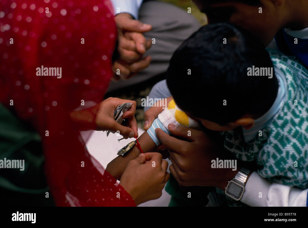 ENGLAND Religion Woman tying thread on arm of boy during the Sacred ...
