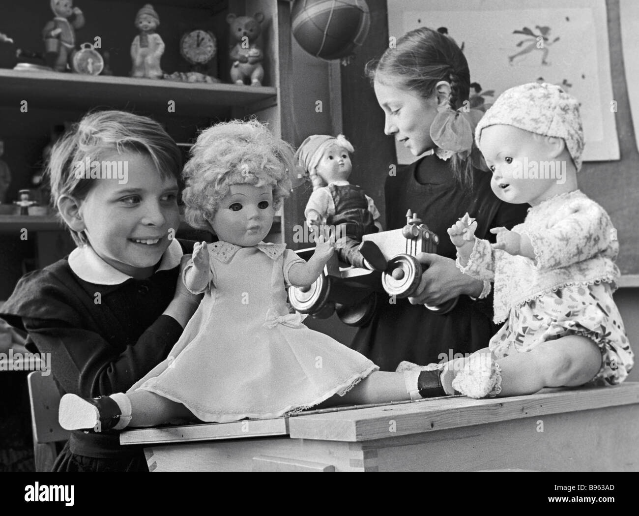 Girls demonstrating dolls clothes during a school lesson Stock Photo ...