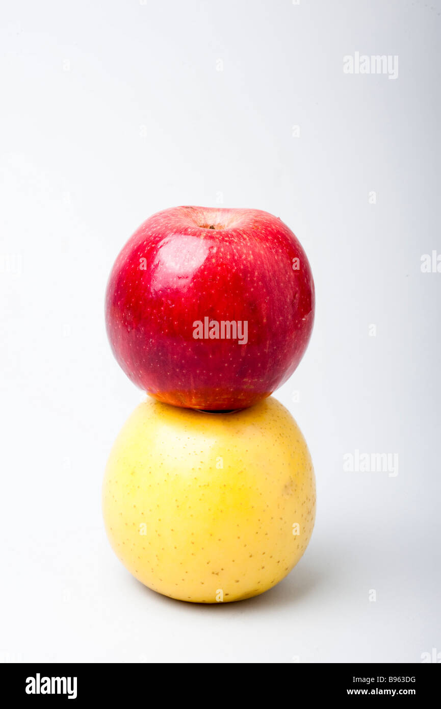 a red apple placed on top of a yellow apple on white background Stock ...
