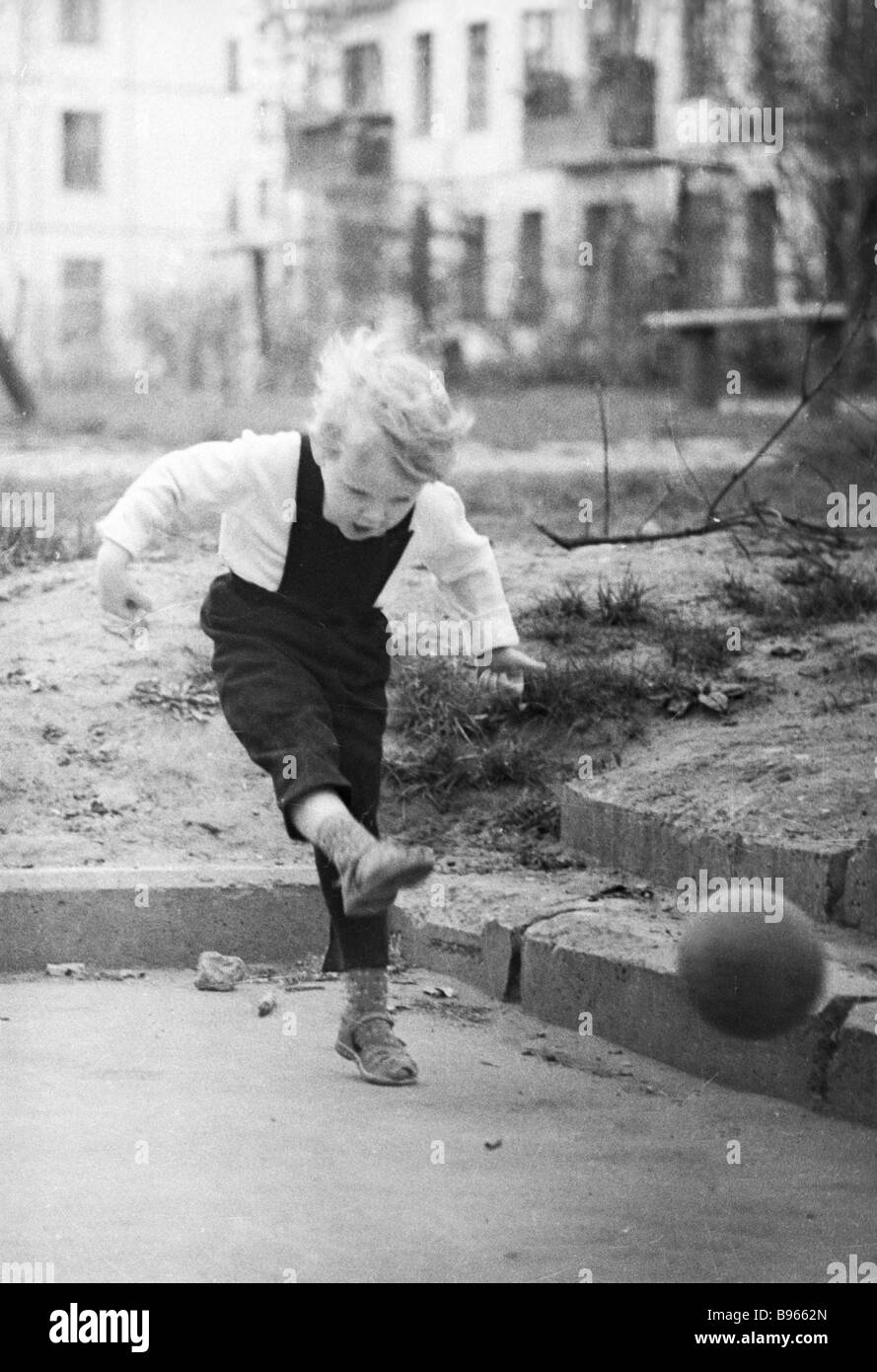 A boy playing the ball in the street Stock Photo - Alamy