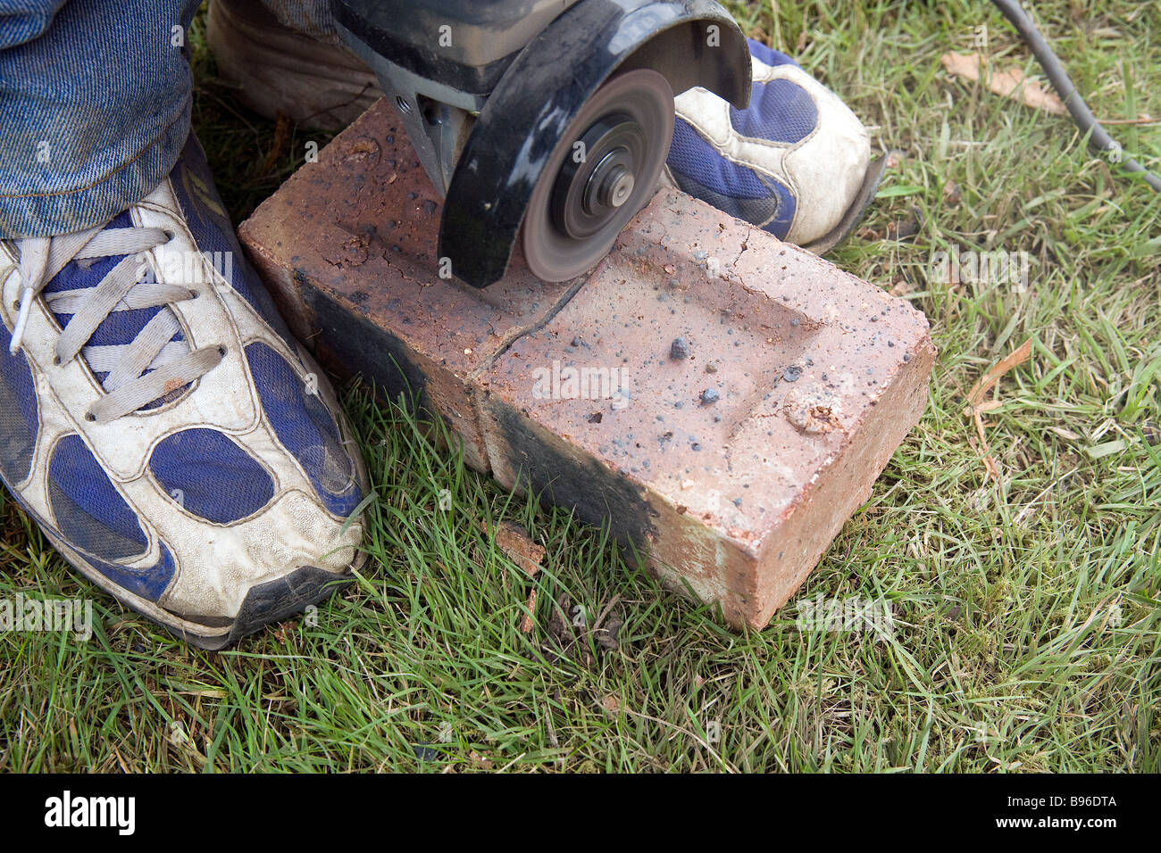 A hand grinder is used to cut a line around a brick giving a straight ...