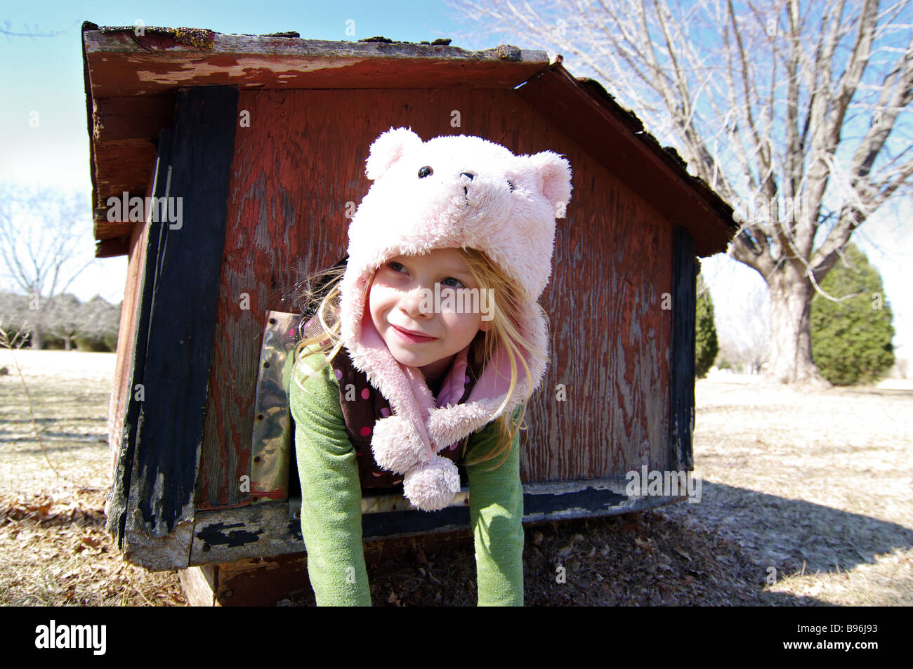 A girl pretends she's an animal as she plays outside in a dog house ...