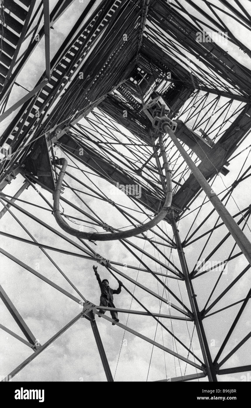 Rig foreman on derrick watches rising pipes Stock Photo - Alamy