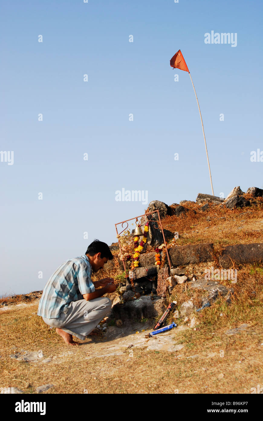 Indian man makes an offering at a small shrine. Arambol, Goa, India ...