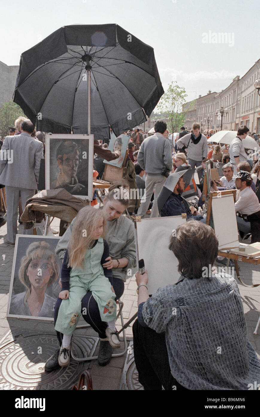 An artist drawing a portrait of a woman with child in Arbat Street ...