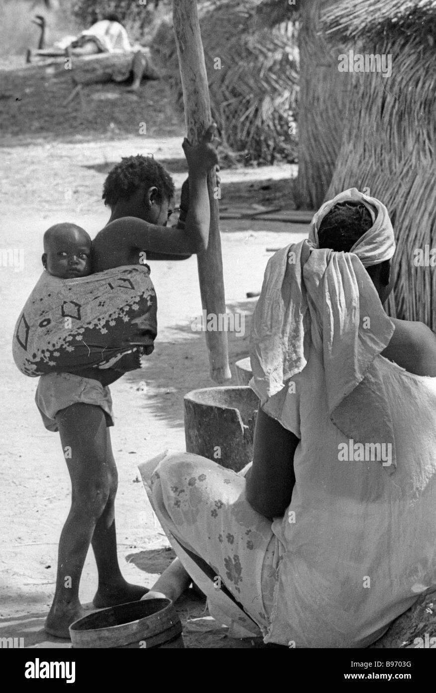 Hausa tribe young villager helping mother with household chores Stock ...