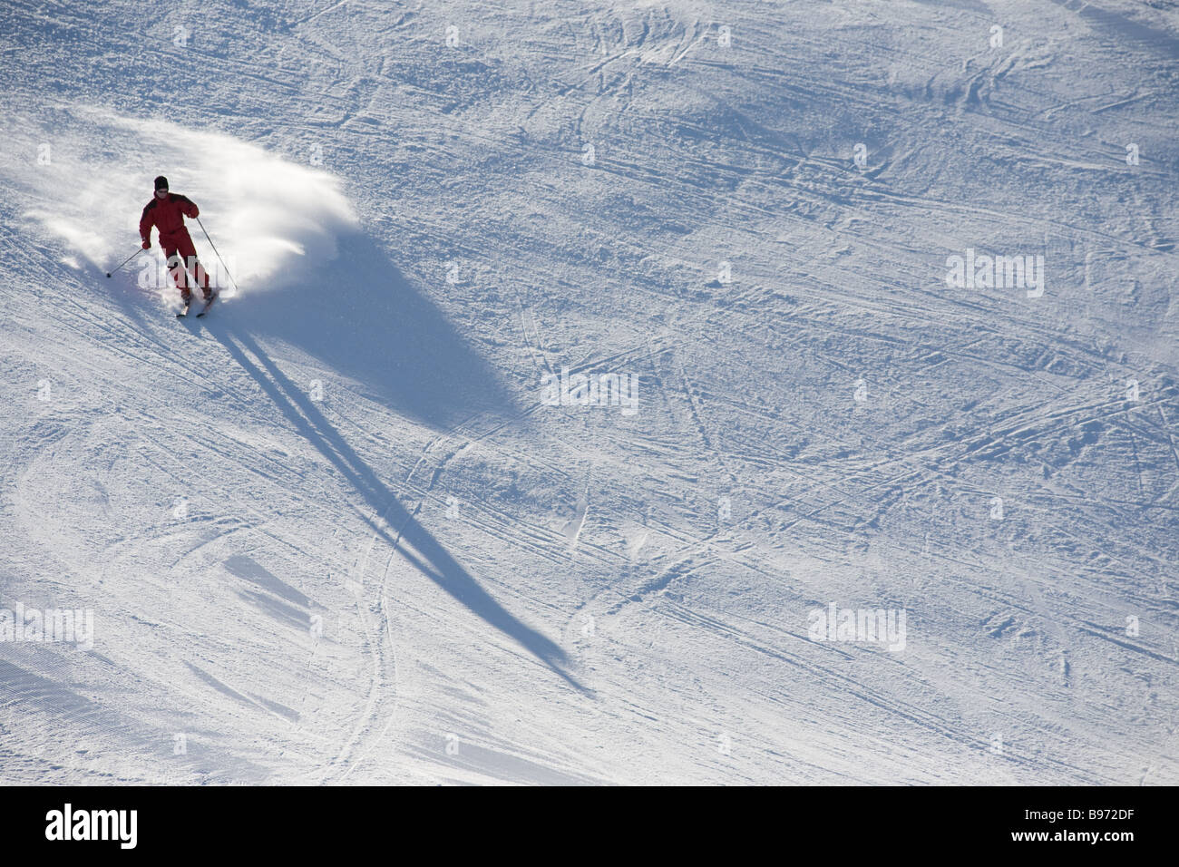 A lone skier descends a steep slope in the early morning sun the powder ...