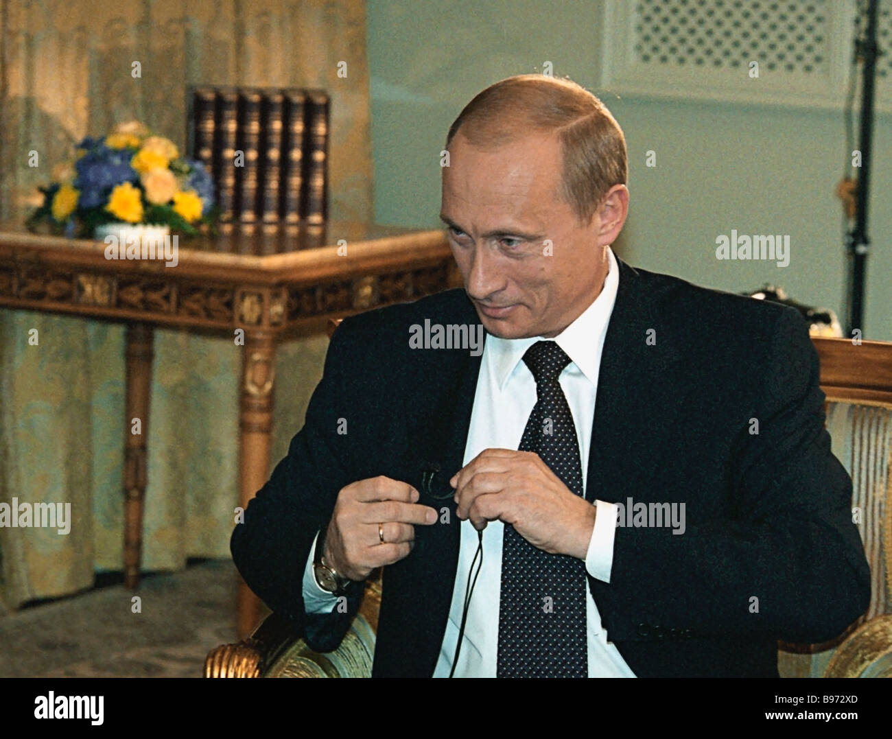 Russian President Vladimir Putin affixes microphone to blazer lapel ...
